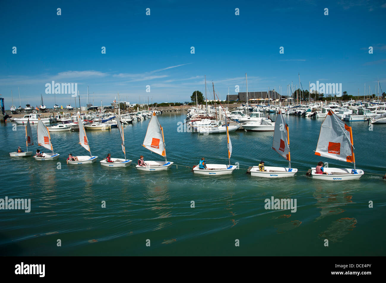 Optimist class sailing boats being towed accross the harbour in Saint ...