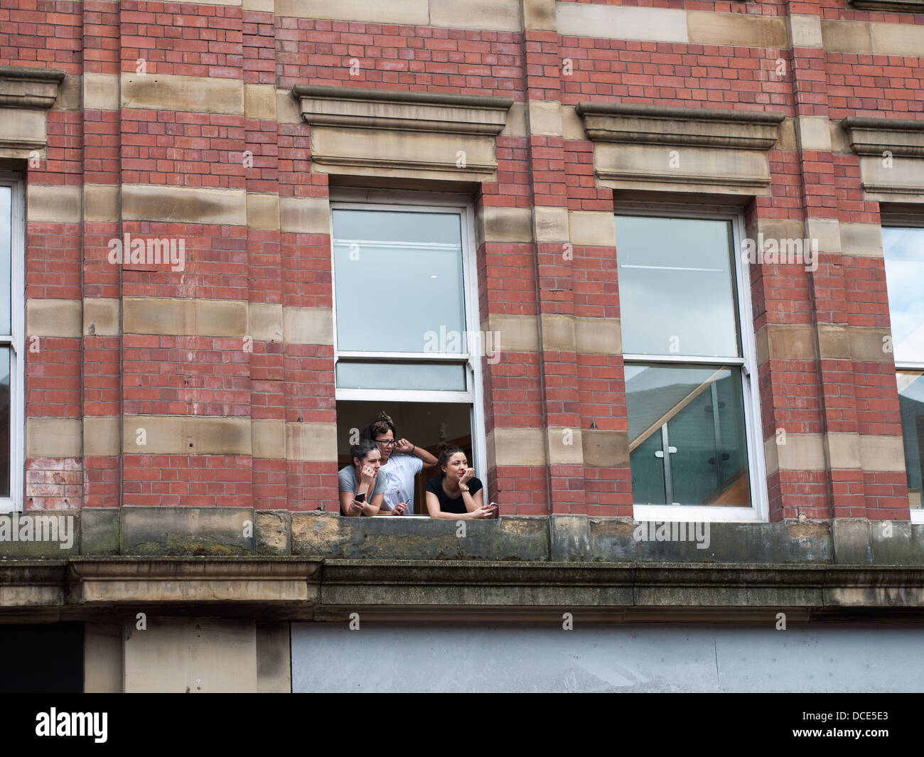 People leaning out of window Stock Photo - Alamy