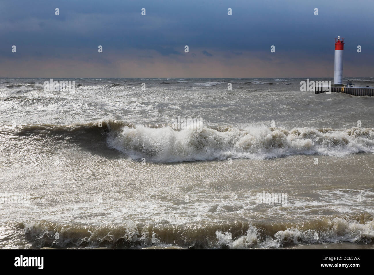 Storm waves crashing on a beach near a lighthouse on lake ontario ...