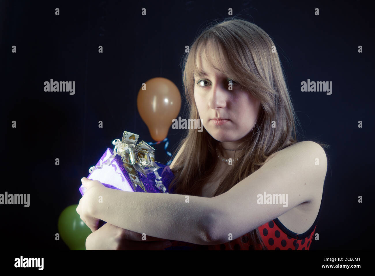 sad girl with a gift box on a dark background with balloons Stock Photo ...