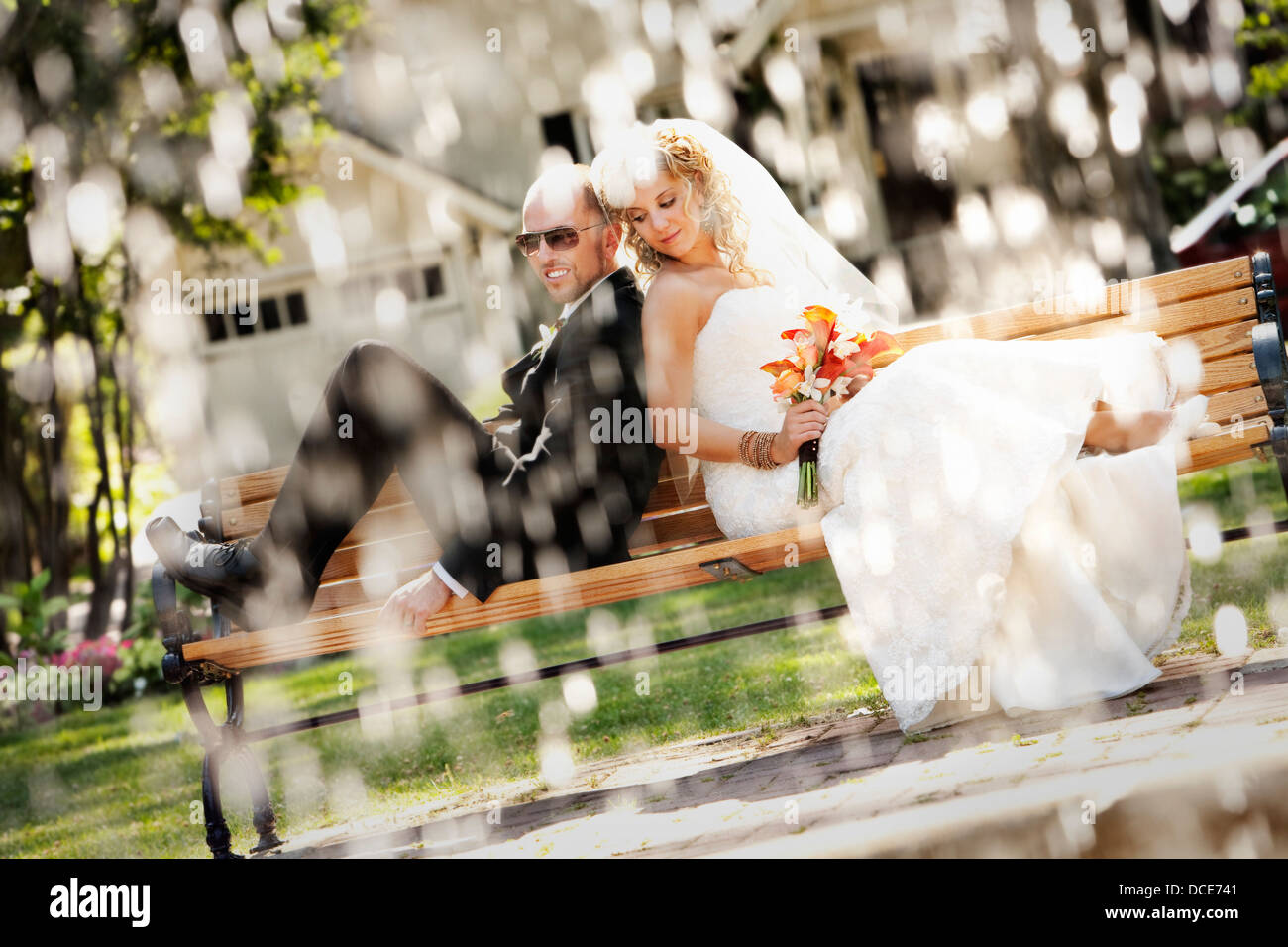 Bride And Groom Relaxing On Park Bench Stock Photo - Alamy