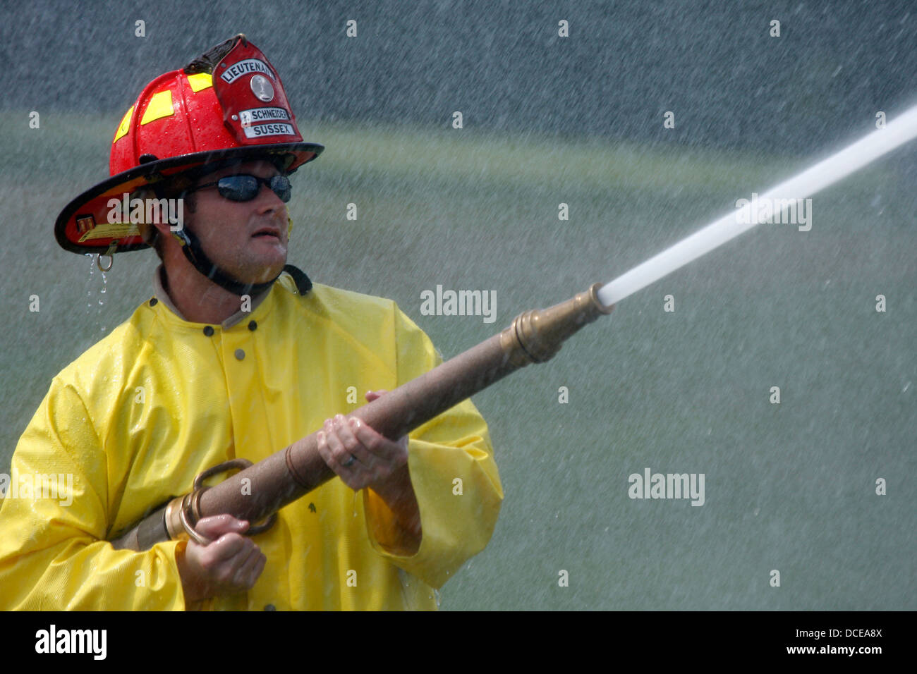 A firefighter spraying water from a hose line Stock Photo - Alamy