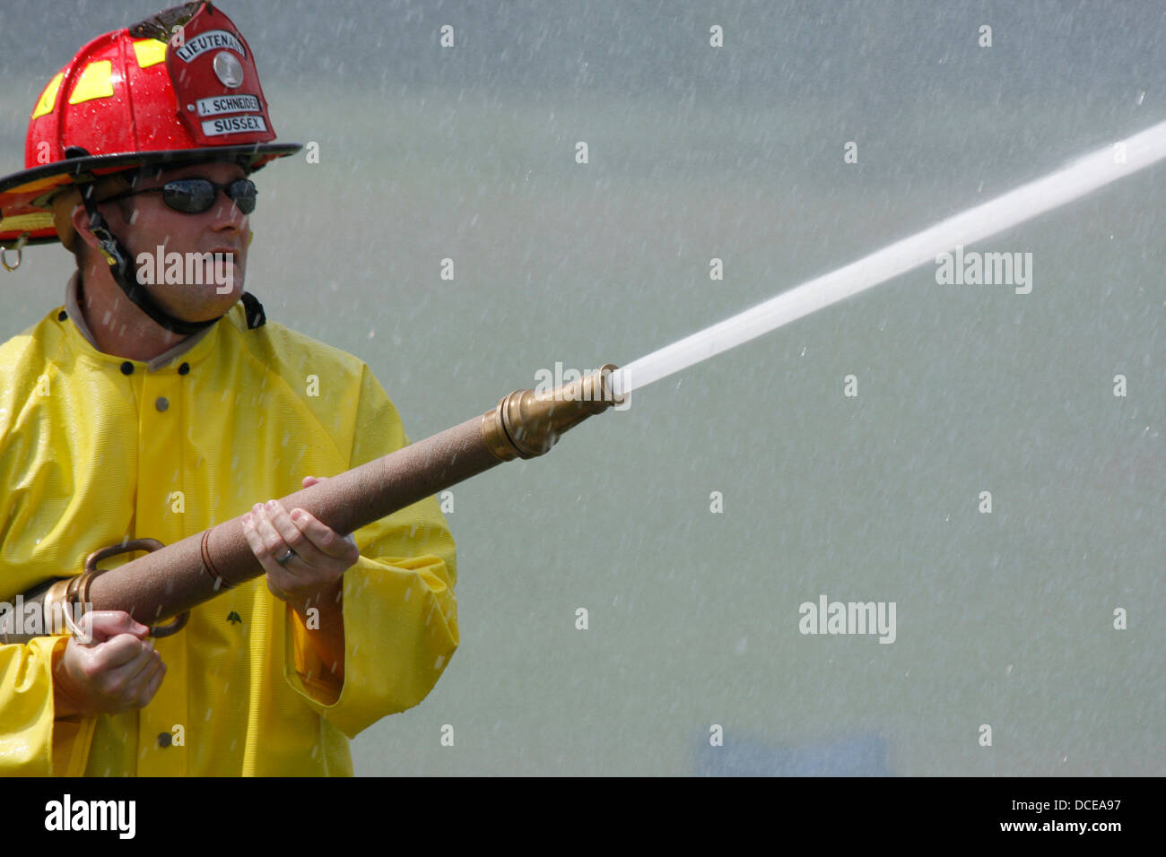 A firefighter spraying water from a hose line Stock Photo - Alamy