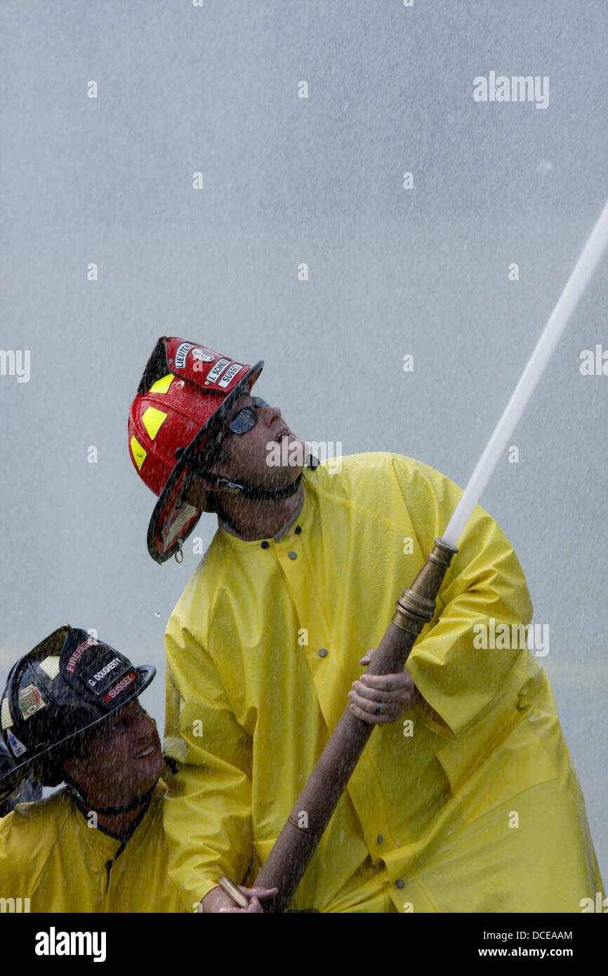 Firefighters spraying water from a hose line Stock Photo - Alamy