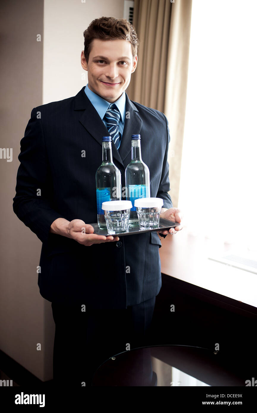 Male butler holding fresh beverages for customers. Posing in front of ...