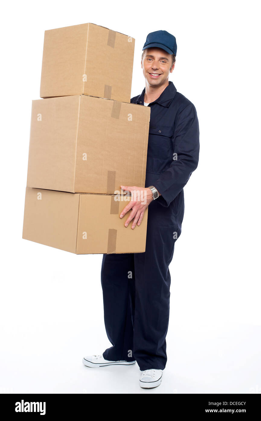 Smiling delivery guy carrying cardboard boxes, full length portrait ...