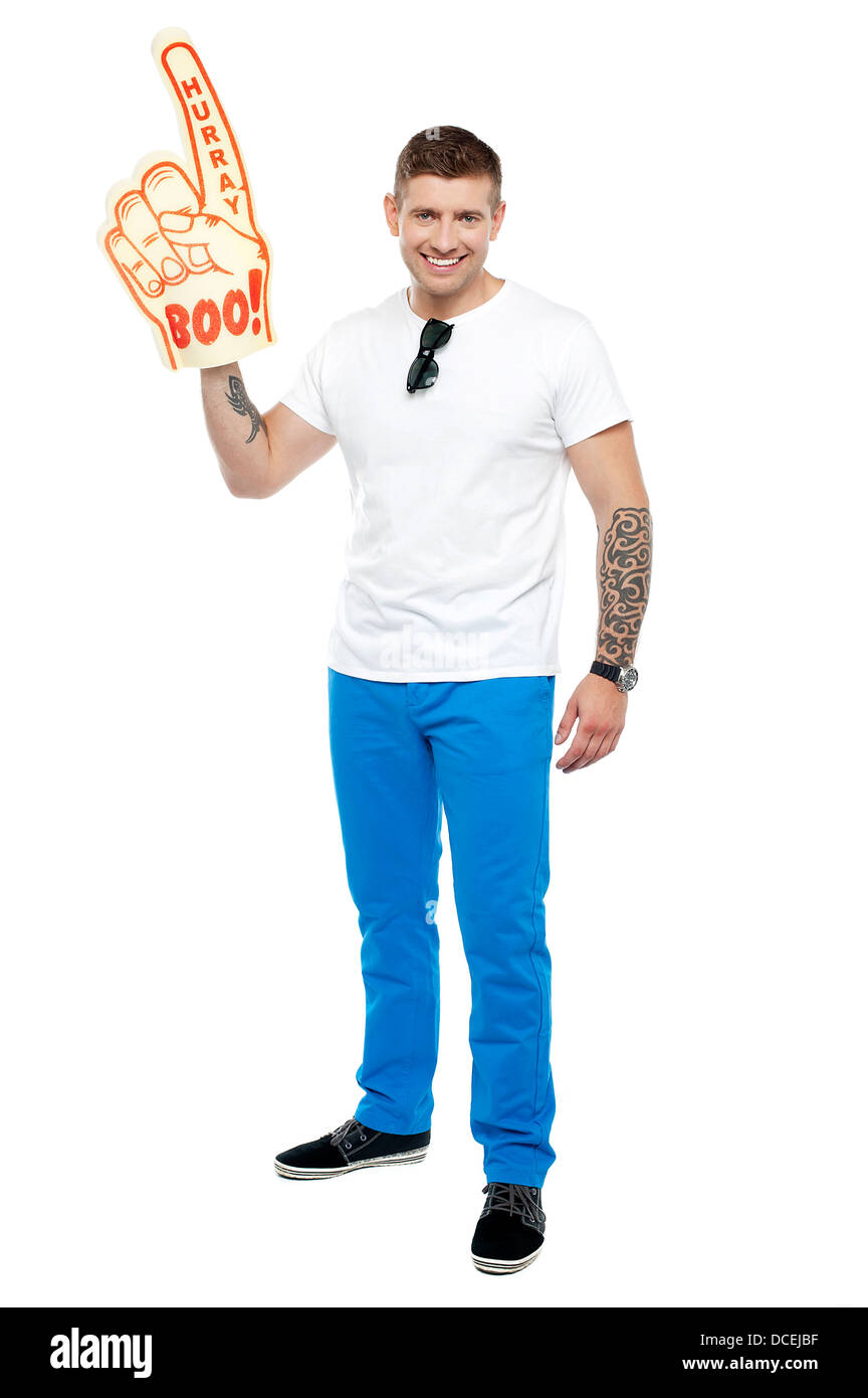 Handsome young smiling sports fan wearing huge foam hand cheering his ...