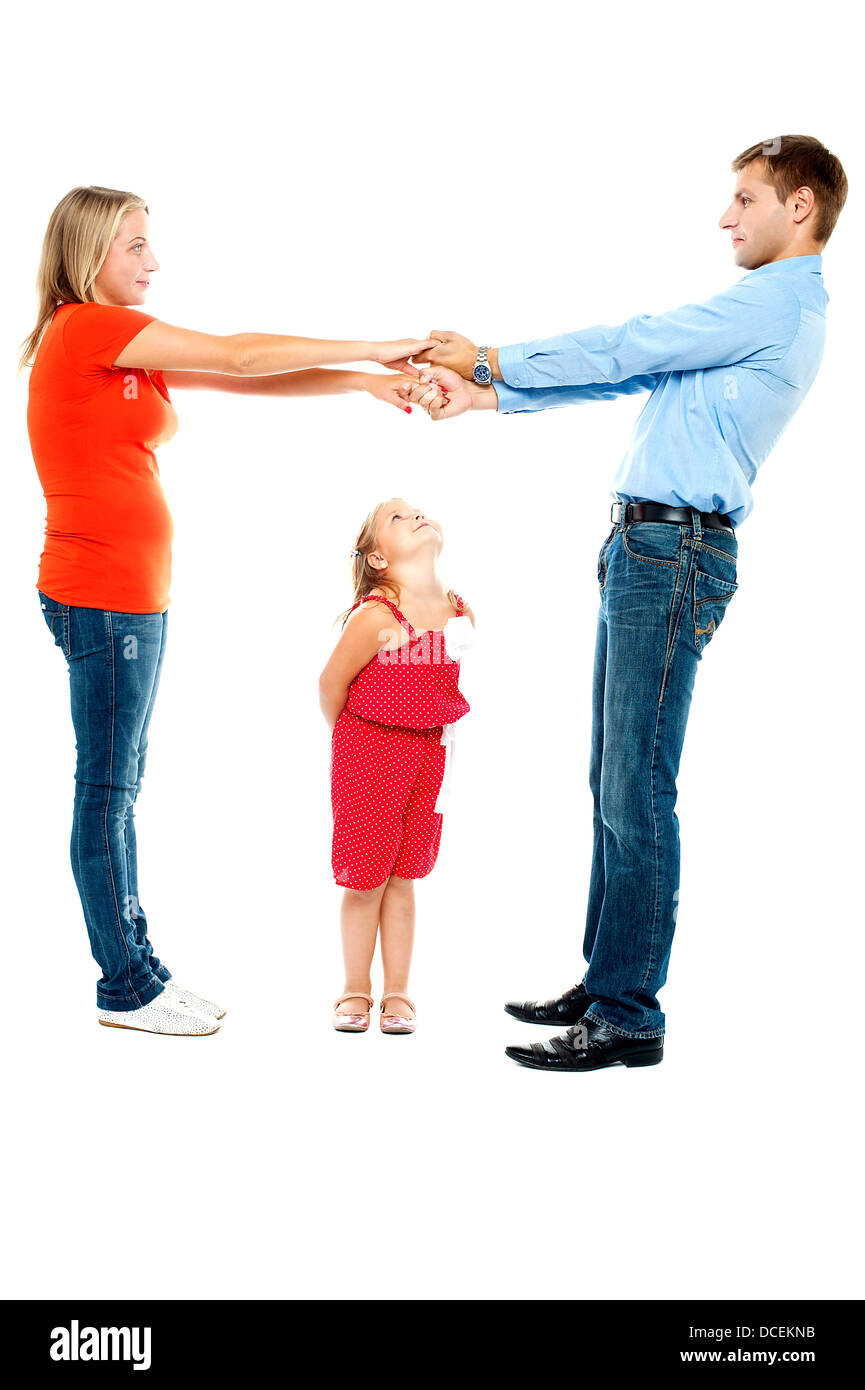 Playful parents holding hands while cute daughter keenly watches them ...