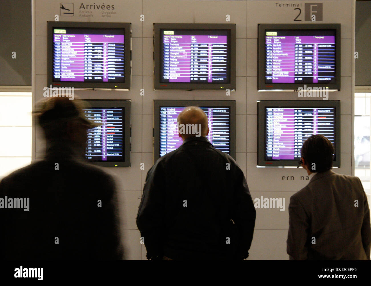 Air travelers look at flight boards at busy airport terminal of Roissy ...