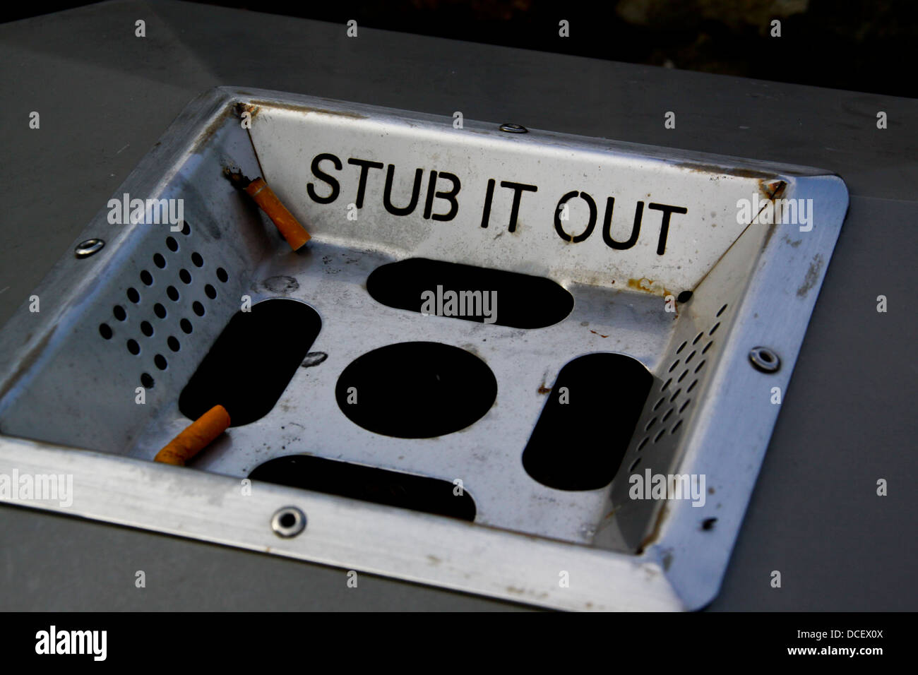 Cigarette ends in public ashtray stub it out sign Stock Photo - Alamy