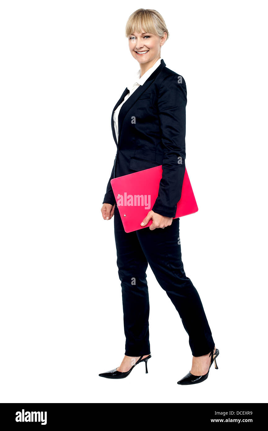 Energetic employee walking with her clipboard. Full length studio shot ...