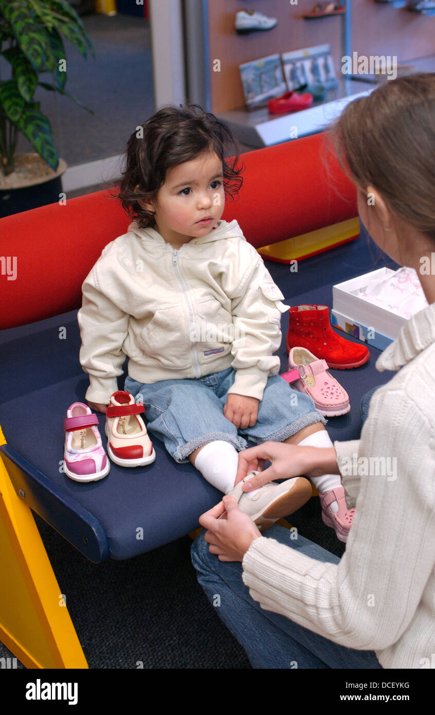Little girl is buying new shoes in the shop Stock Photo - Alamy