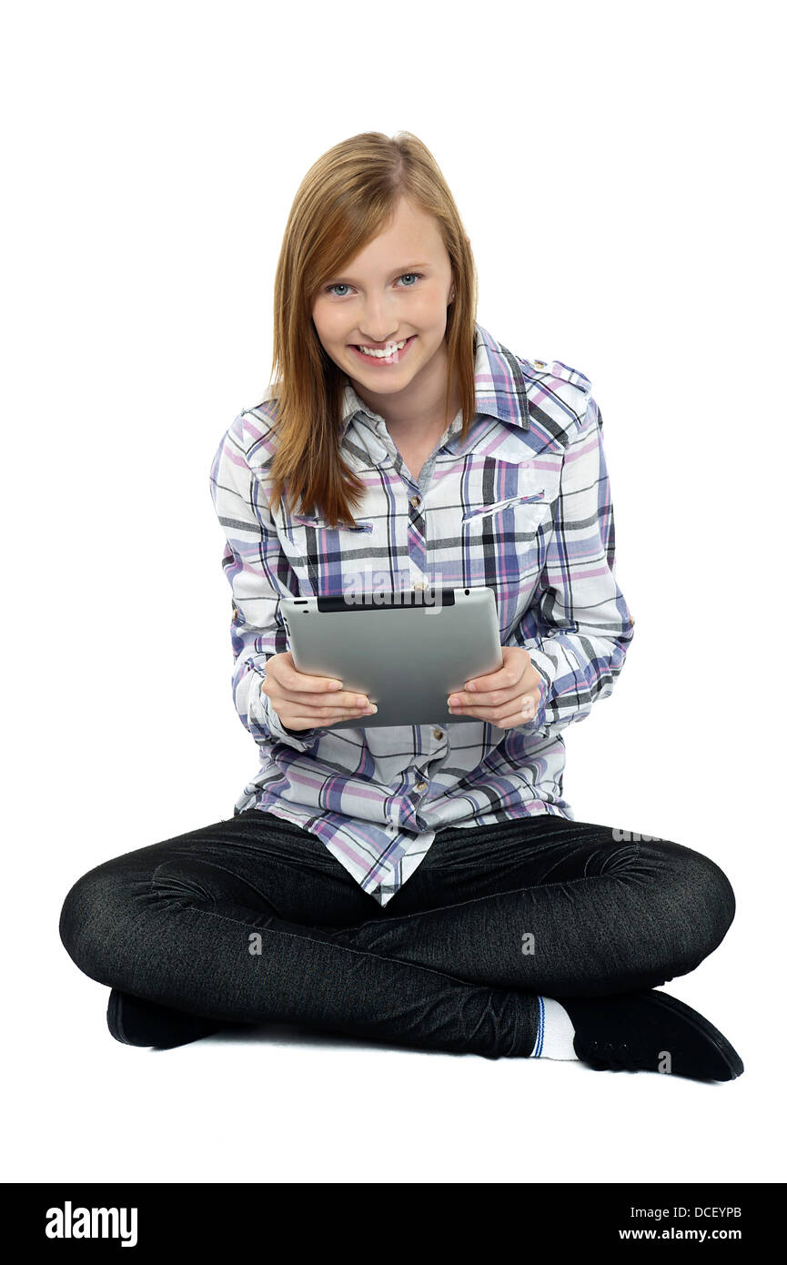 Smartly dressed teenager surfing on tablet pc. Sitting with legs ...