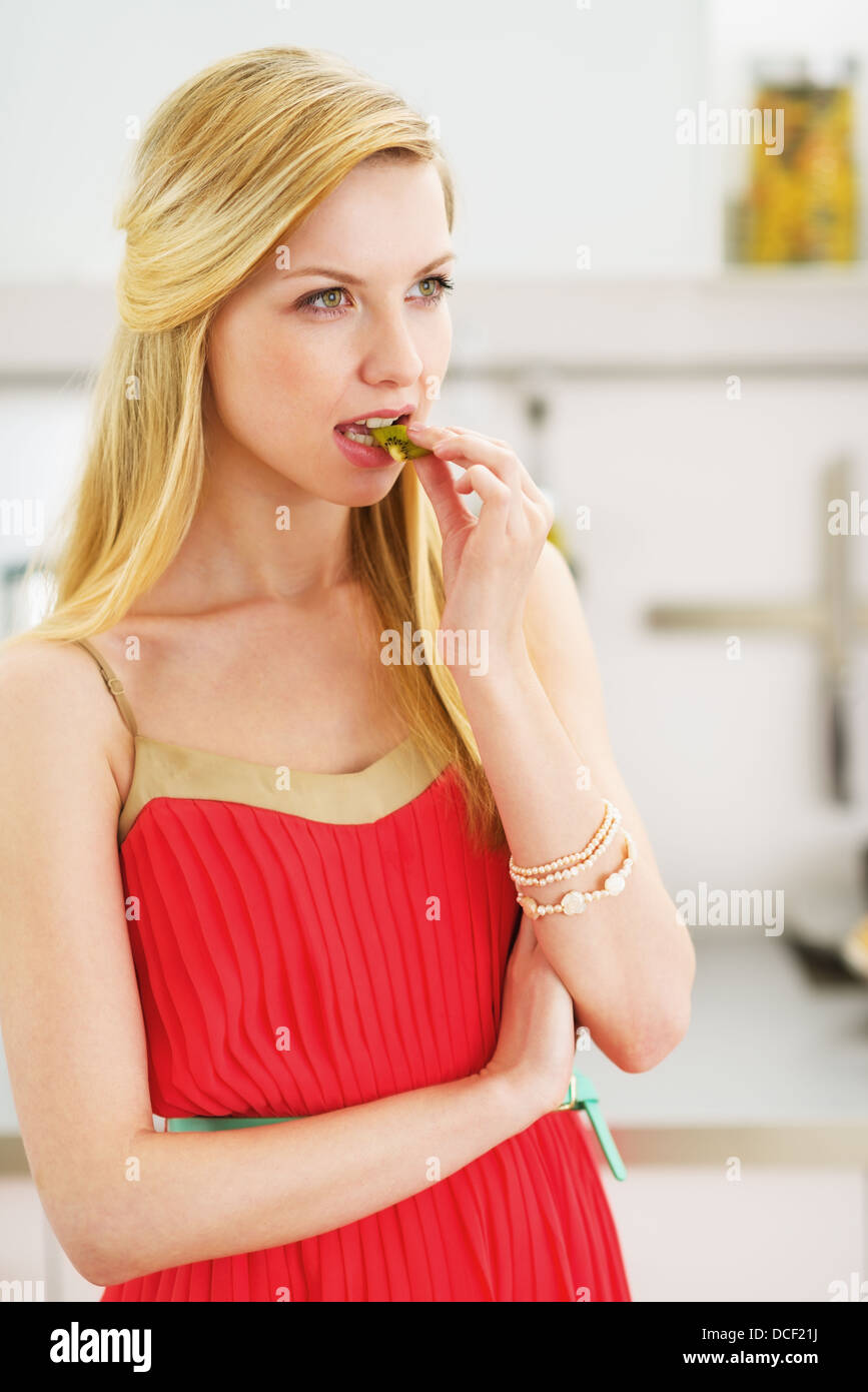 Thoughtful young woman having snack in kitchen Stock Photo - Alamy