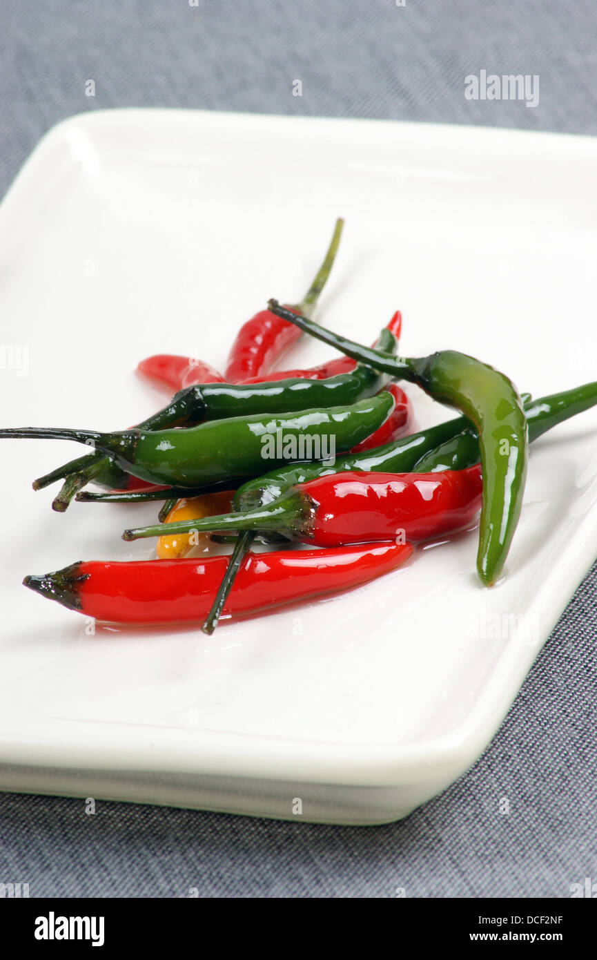green and red hot paprika on a white plate Stock Photo - Alamy