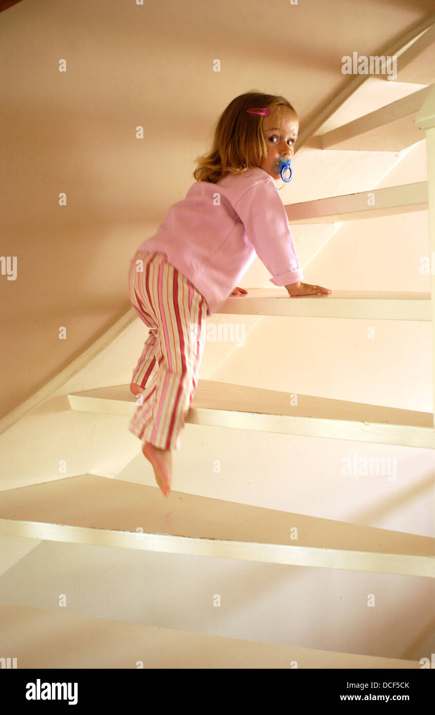 Toddler girl is climbing the stairs Stock Photo - Alamy