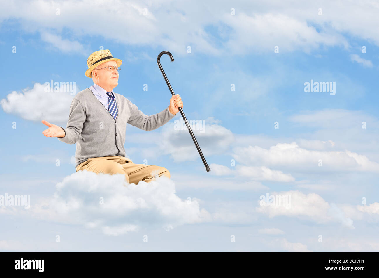Senior man floating on a cloud and spreading arms while holding a cane ...