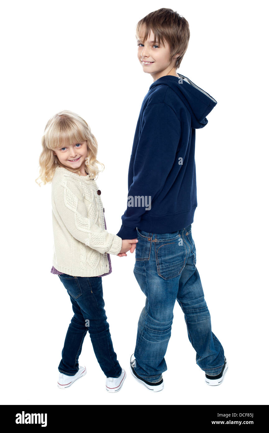 Delightful kids turning back and facing camera. Brother holding sisters ...