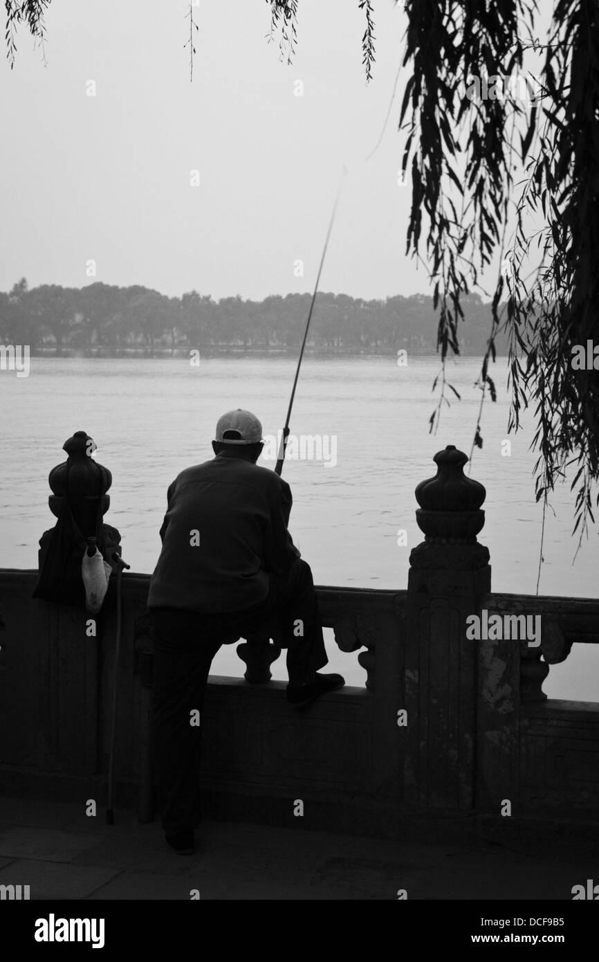 A man fishes on the 17 Arch Bridge in the Summer Palace gardens ...