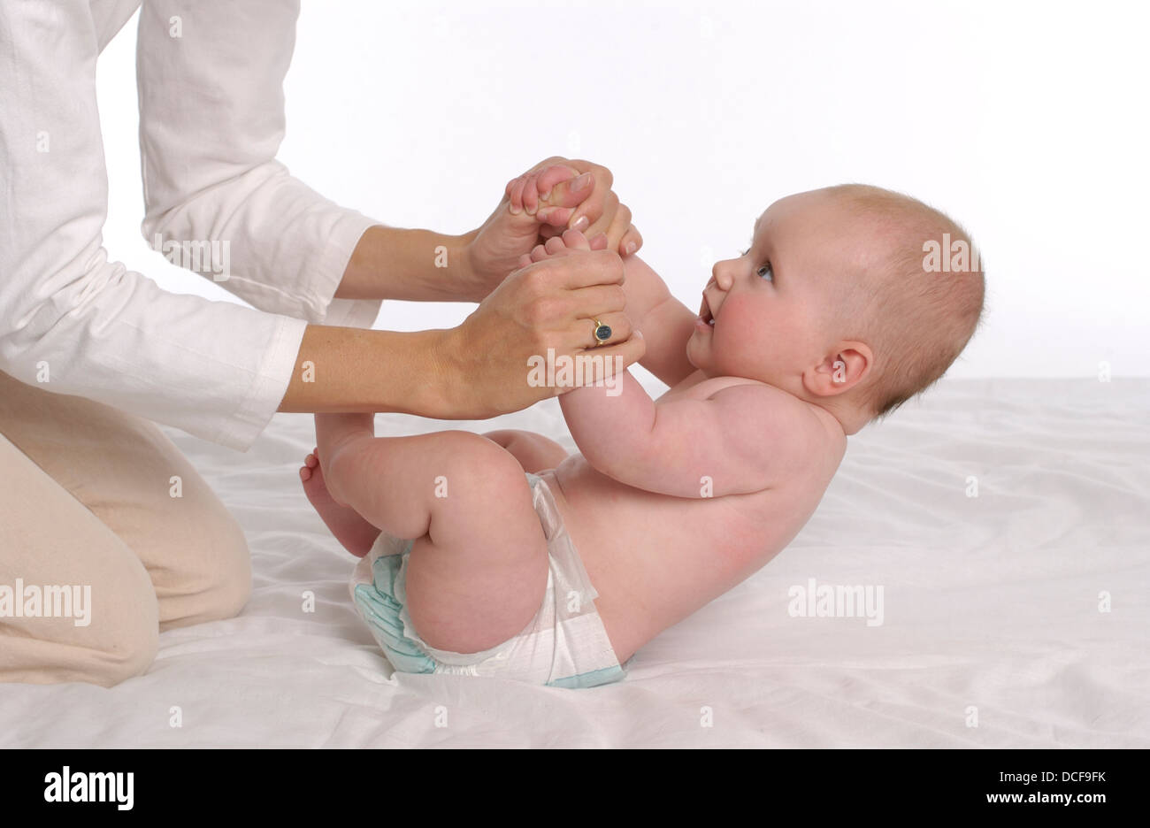 Baby girl pulling up on mothers hands Stock Photo - Alamy