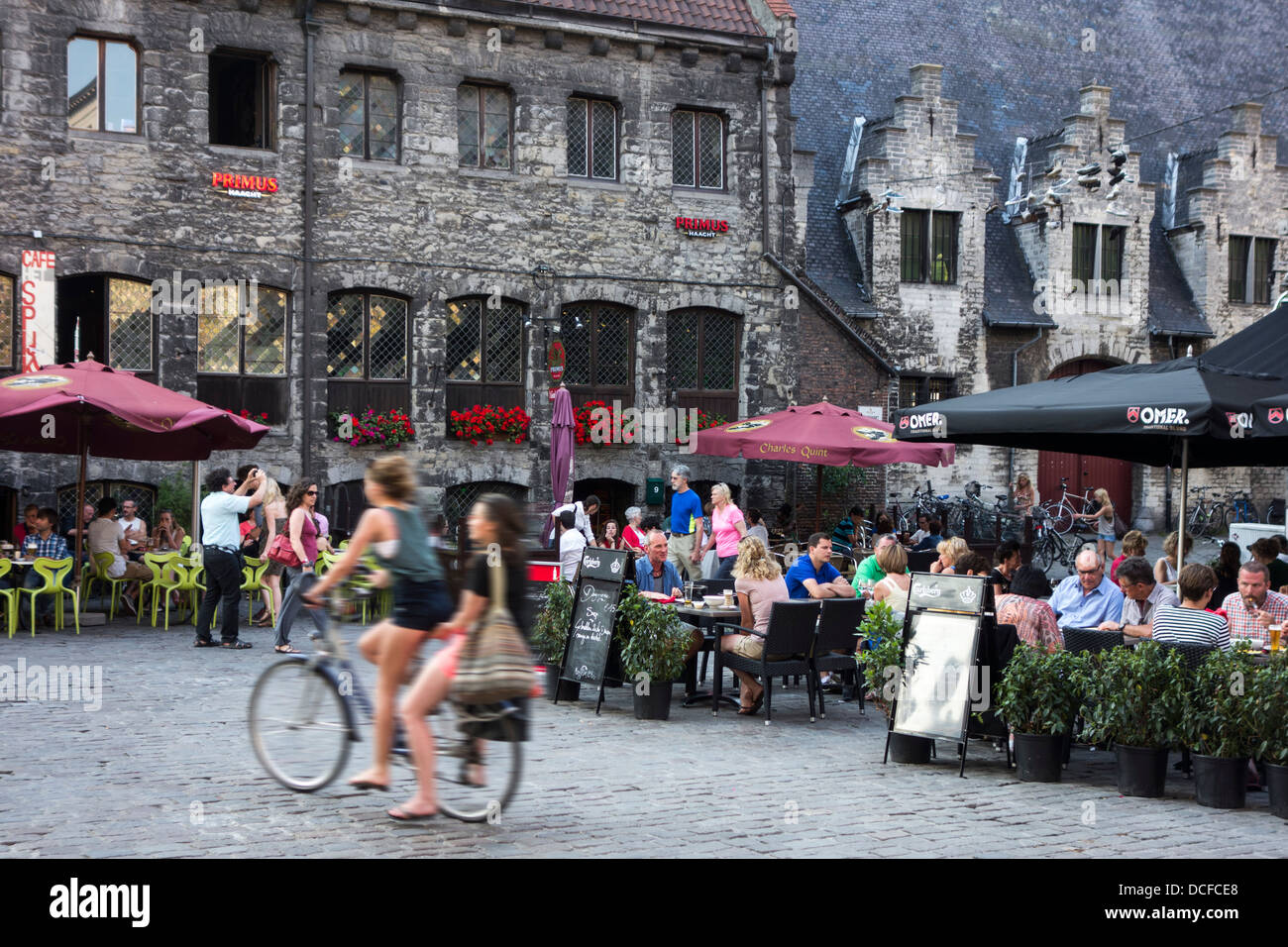 Girls riding bike and tourists at pavement cafés in the historic center ...