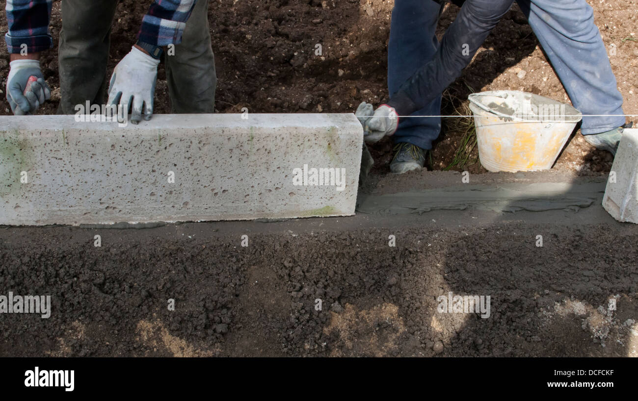 Construction site - Workers laying concrete curbs Stock Photo - Alamy