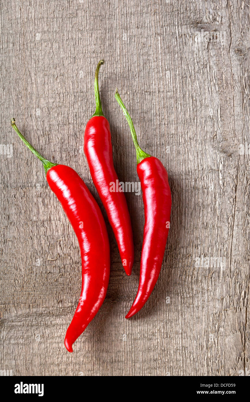 Red Chillies on Rustic Background - three red chillies on a plank or ...