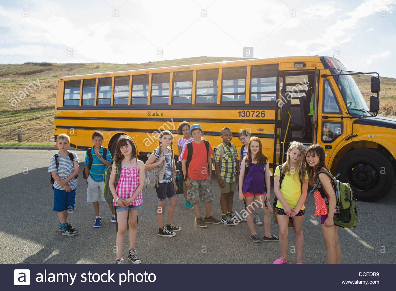 Portrait of children with backpacks standing by school bus Stock Photo ...