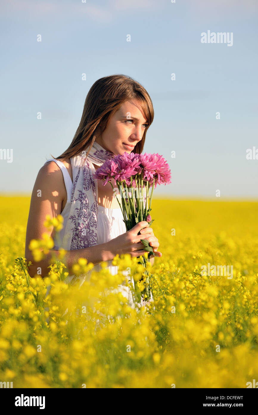 Woman Sniffing Purple Flowers While Standing In Golden Field Stock ...
