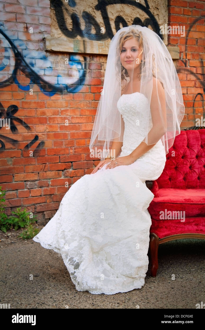 Bride Sitting On The Edge Of A Red Sofa Outdoors Stock Photo - Alamy