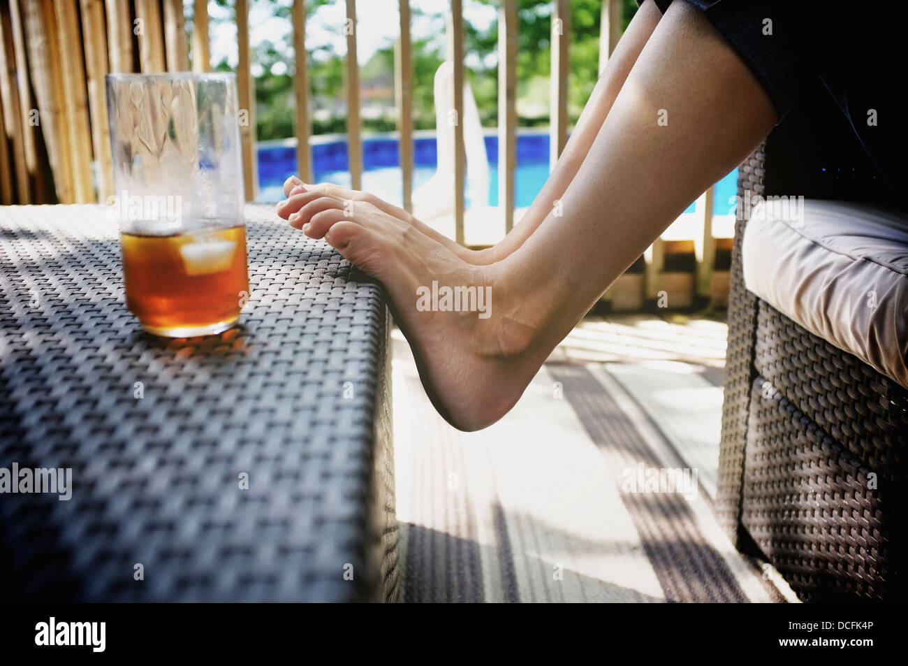 Woman's Feet On Outdoors Rattan Furniture With Glass Of Iced Tea Stock ...
