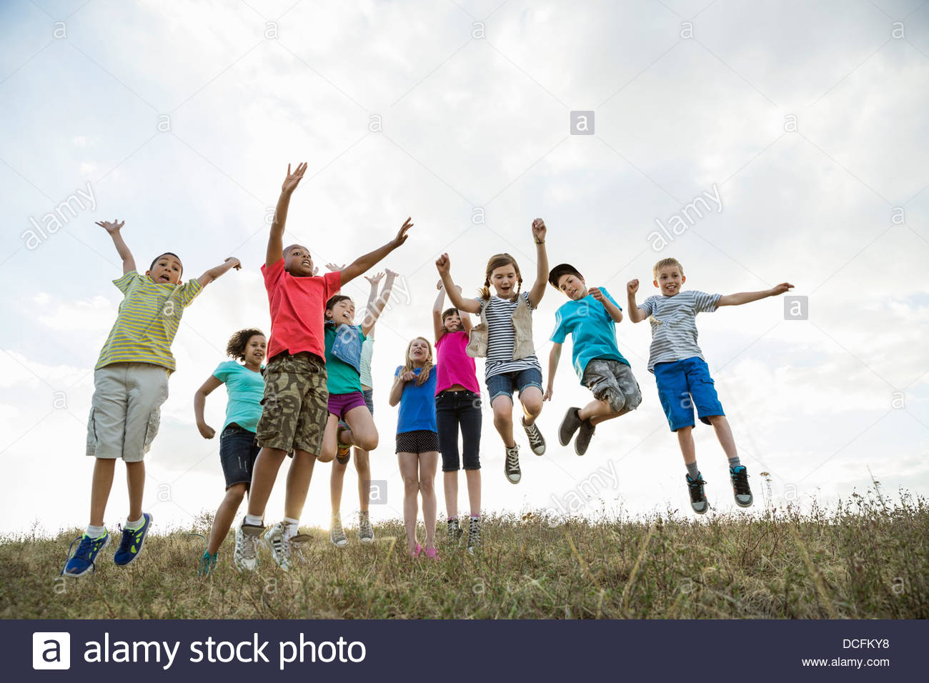Group of kids jumping together outdoors Stock Photo - Alamy