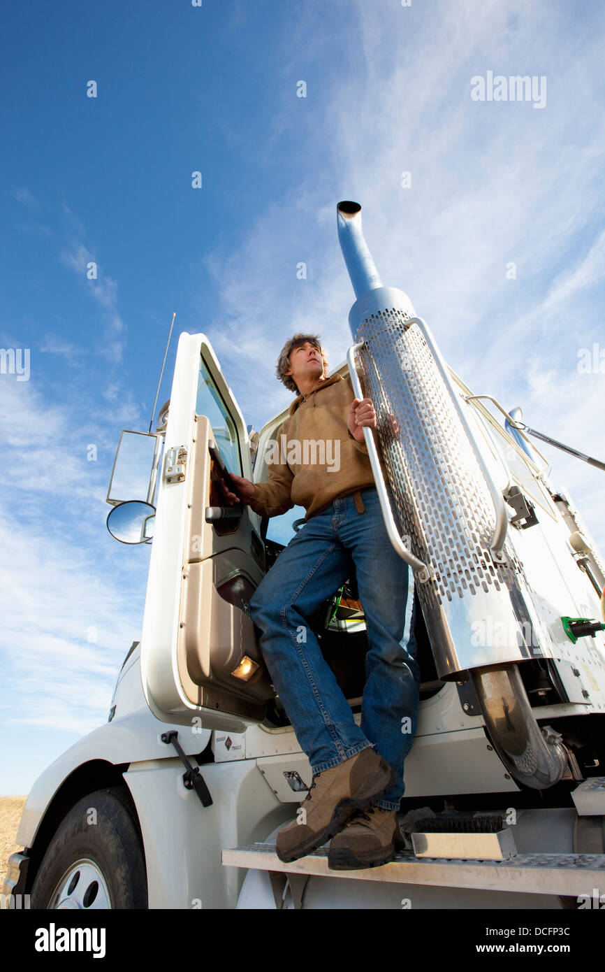 A Man Standing On The Step Of The Cab Of His Truck; Three Hills ...