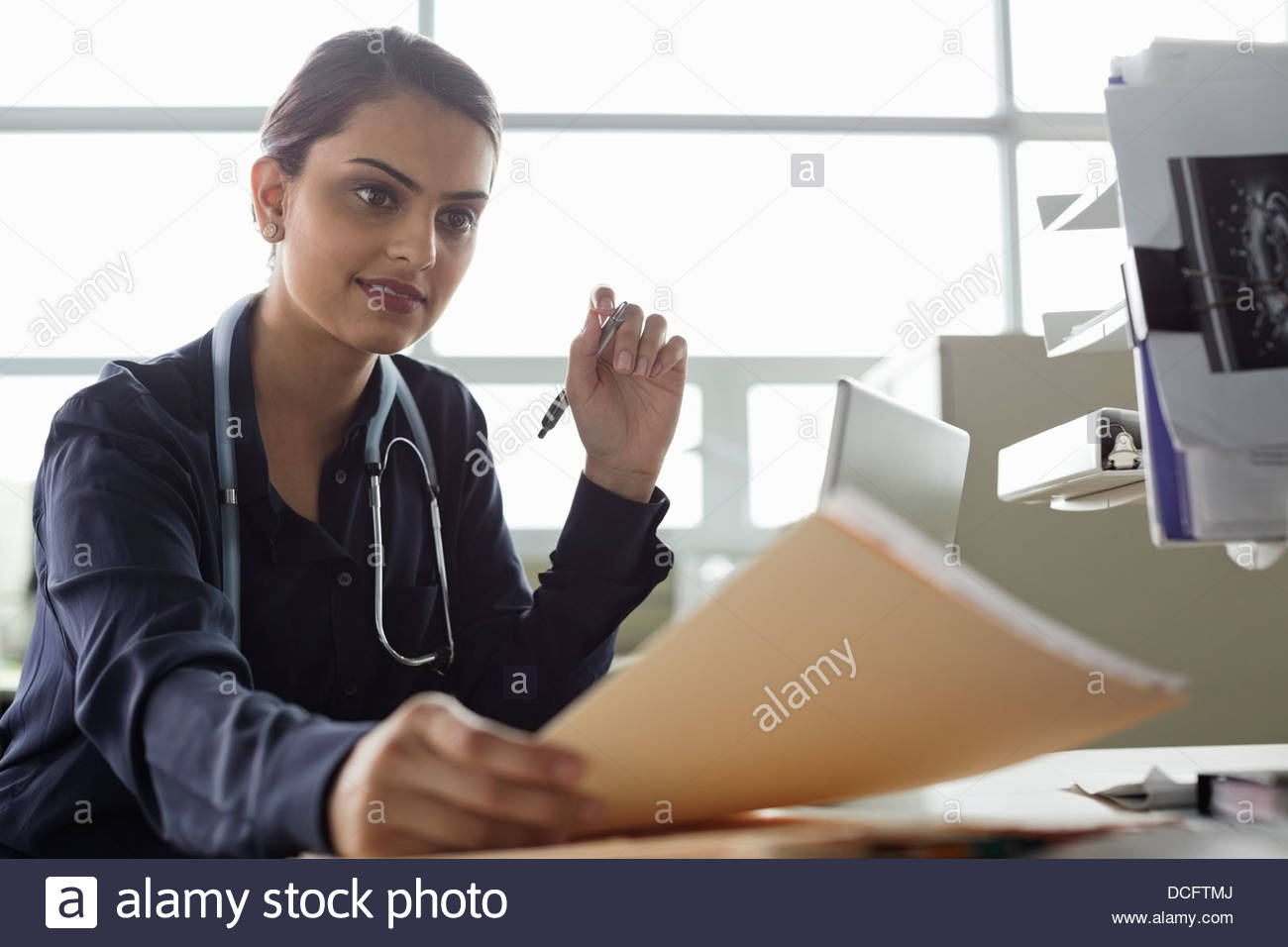 Female doctor reading documents Stock Photo - Alamy