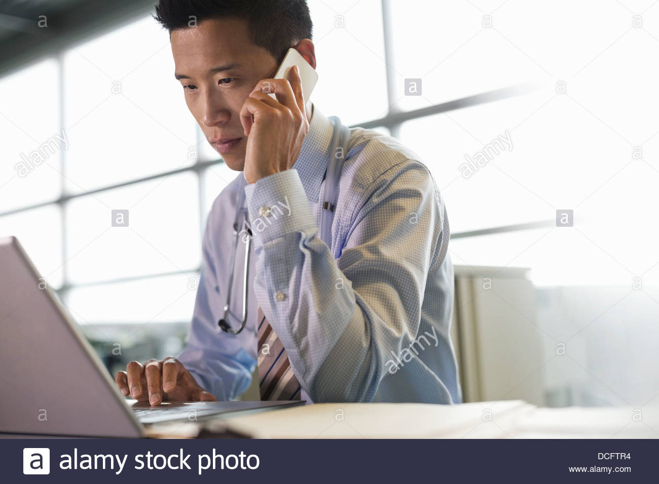 Male doctor multi-tasking Stock Photo - Alamy