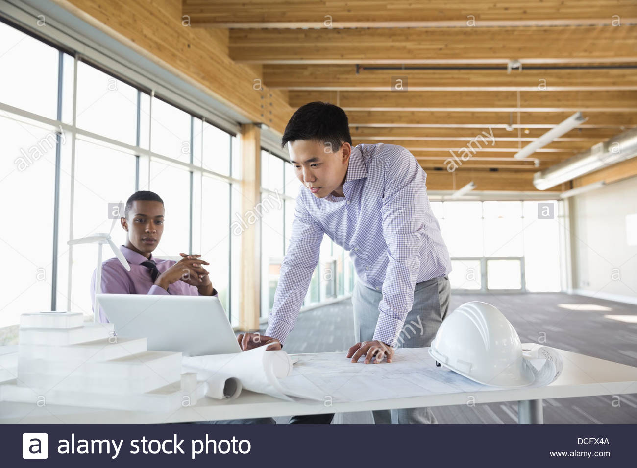 Engineers discussing plans over laptop Stock Photo - Alamy