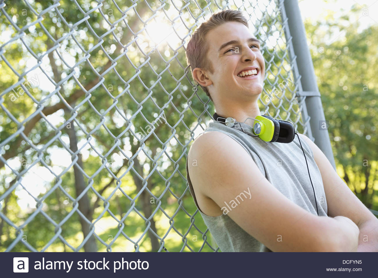 Smiling teen leaning on chain-link fence Stock Photo - Alamy