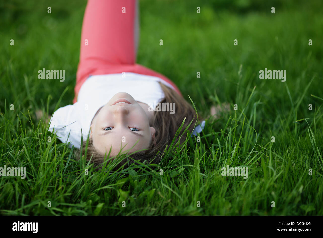 young attractive girl lying on the grass and looking to the camera ...