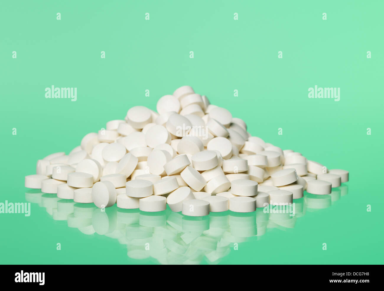 Stack of pills towards green background Stock Photo - Alamy