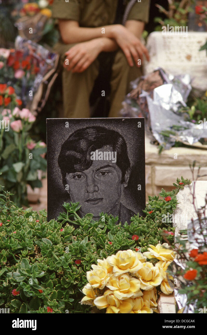 An Israeli female soldier sits next to the grave of a fallen soldier on ...