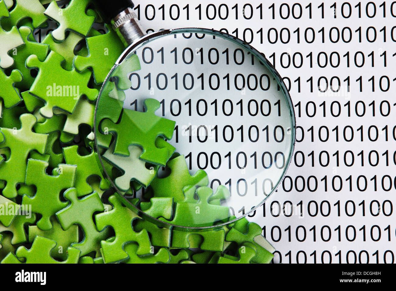 puzzles and magnifying glass on a binary code Stock Photo - Alamy