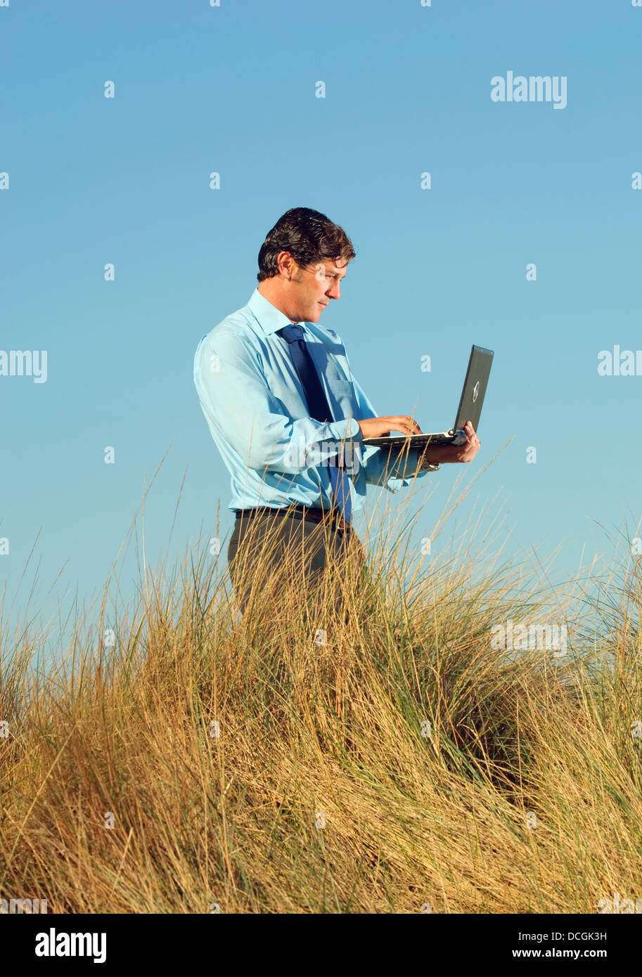 Man Working On Laptop Outdoors Surrounded By Beach Grass Stock Photo ...