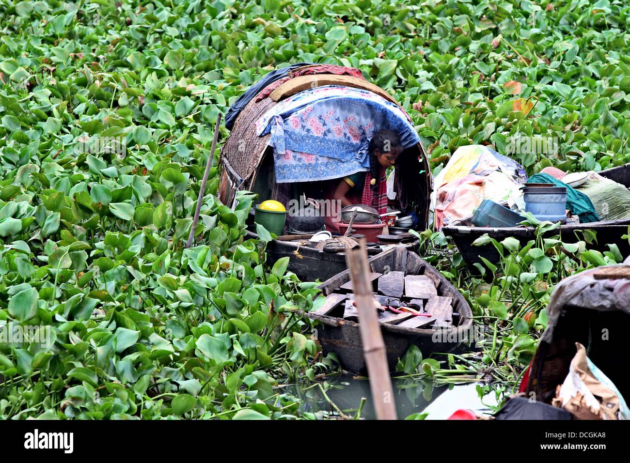 Bangladeshi river gypsy works on her boat as a boat man attempts to ...
