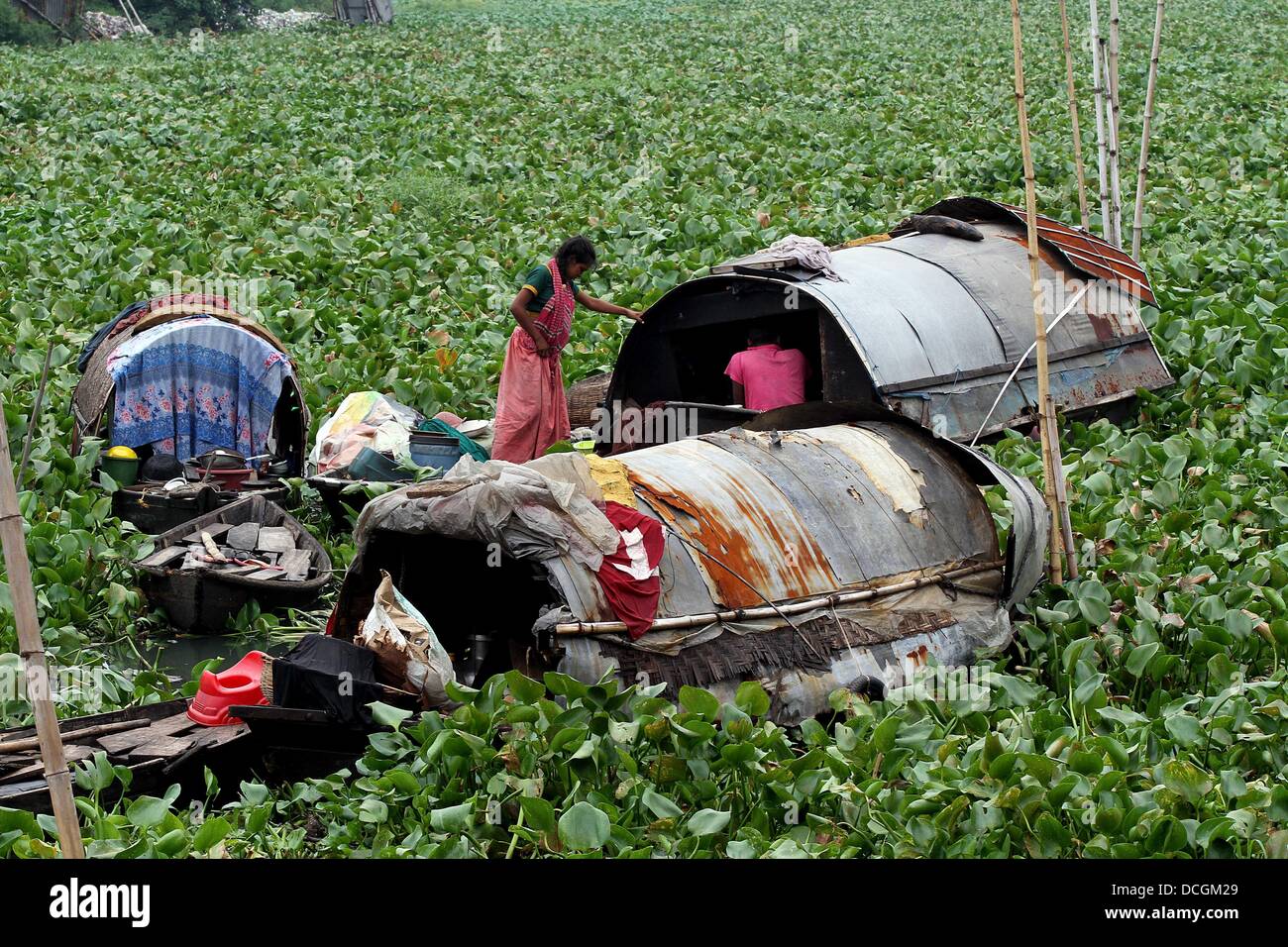 Bangladeshi river gypsy works on her boat as a boat man attempts to ...