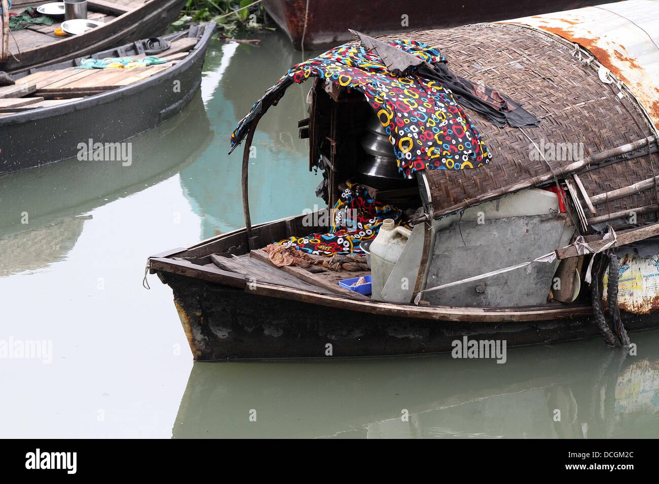 Bangladeshi river gypsy works on her boat as a boat man attempts to ...
