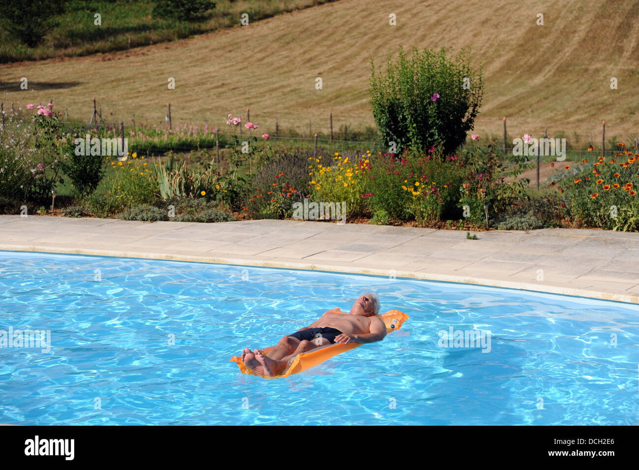 Man sunbathing on a lilo in a swimming pool at holiday gite in the Lot ...