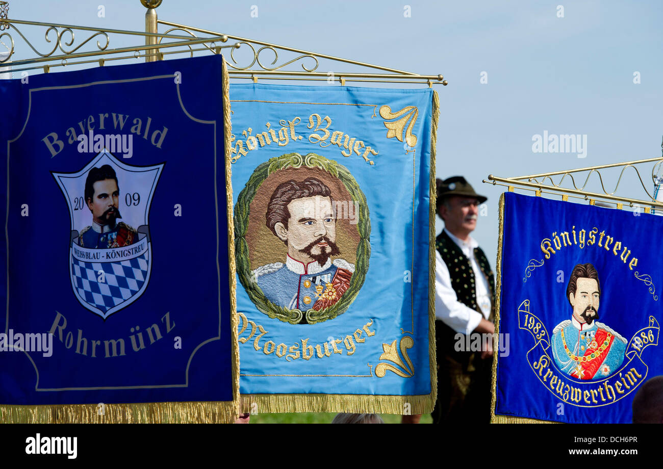 A man in traditional Bavarian costume stands between flags with ...