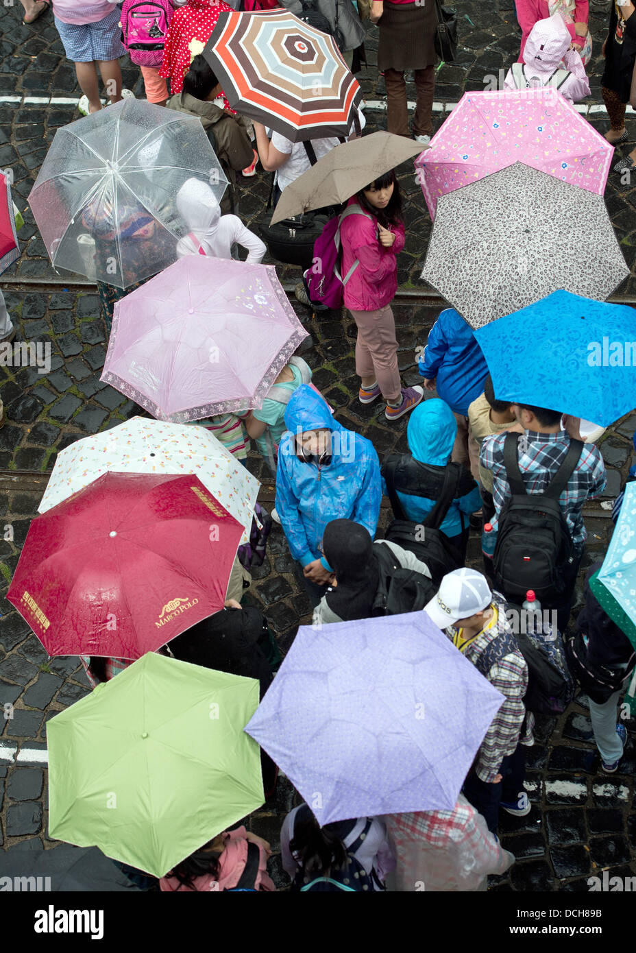 Tourists from Asia protect themselves from rain with umbrellas ...