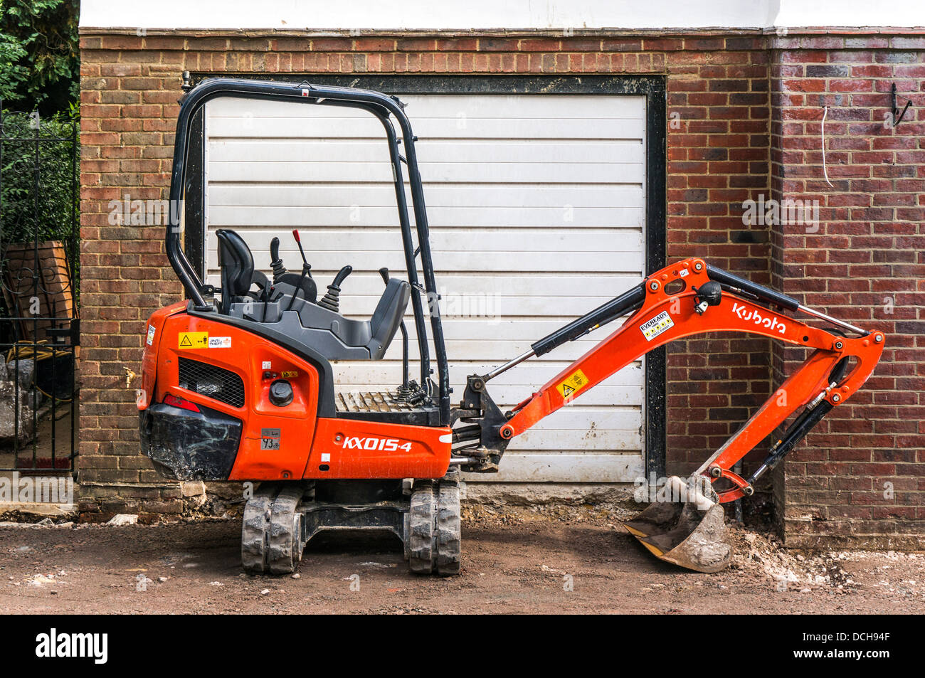 A hydraulic digger, parked outside a garage, used to prepare the ground ...