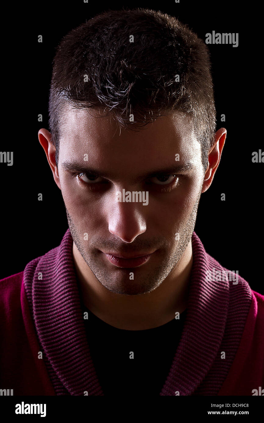 Face view of a young urban man with a mean look isolated on a black ...